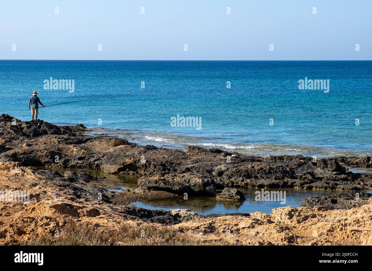 Man standing on rocks and fish in the sea hi-res stock photography and ...