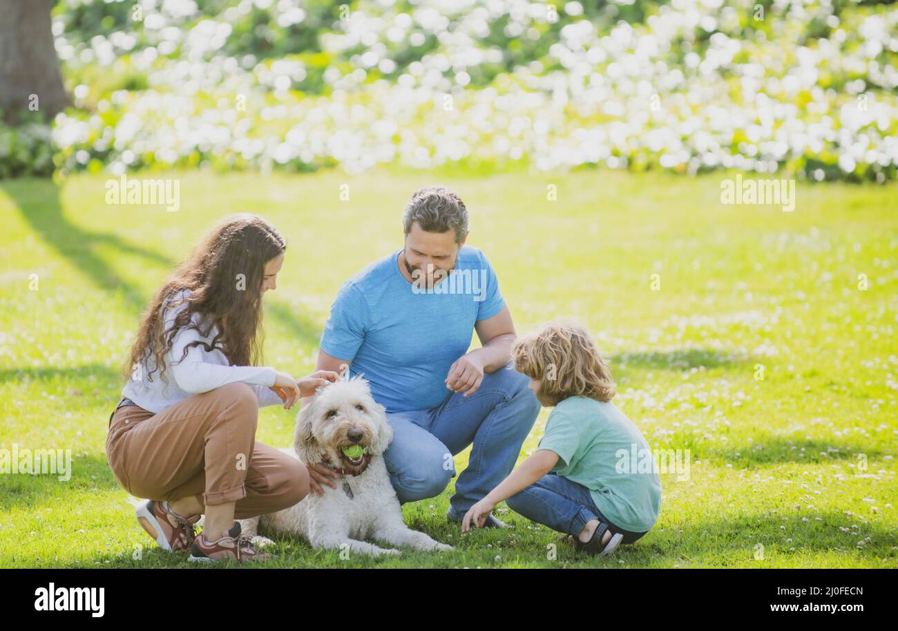 Family relaxing in garden with pet dog. The concept of a happy family. Parents and children on ...