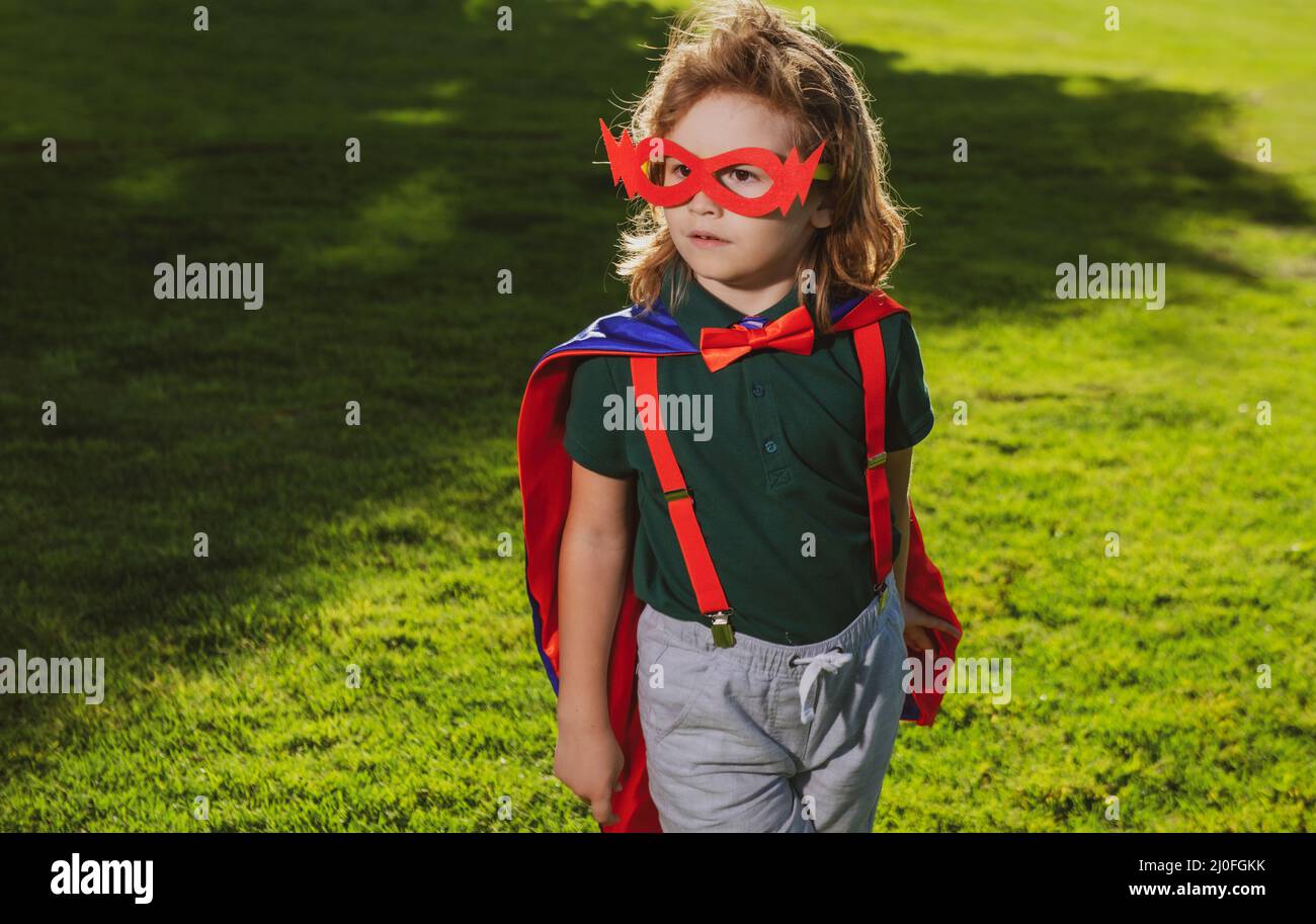 Superhero kid against green background outdoor. Childhood, success and ...