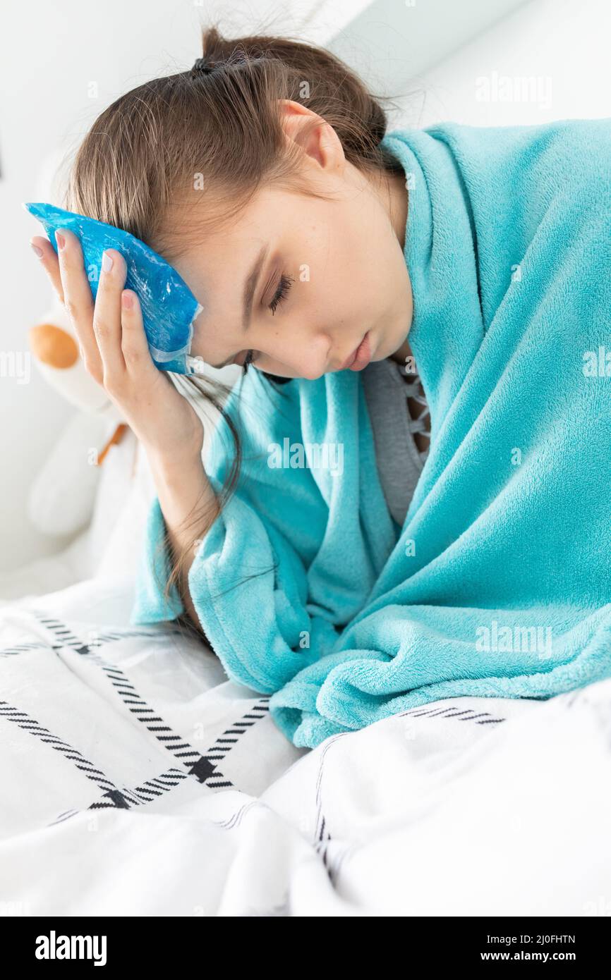 The teenager puts cold compresses on her head to reduce the high ...