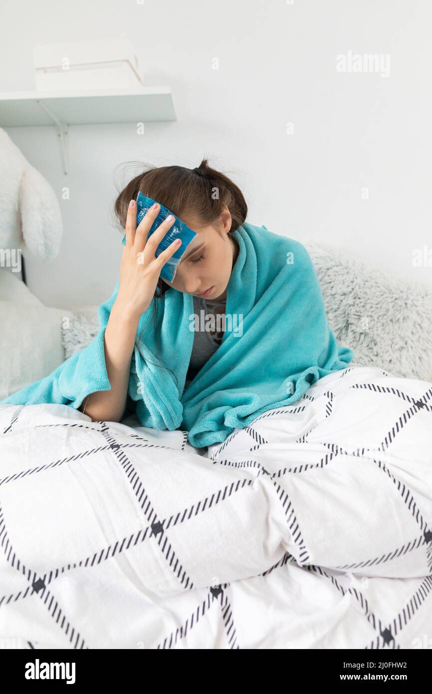 The teenager puts cold compresses on her head to reduce the high ...