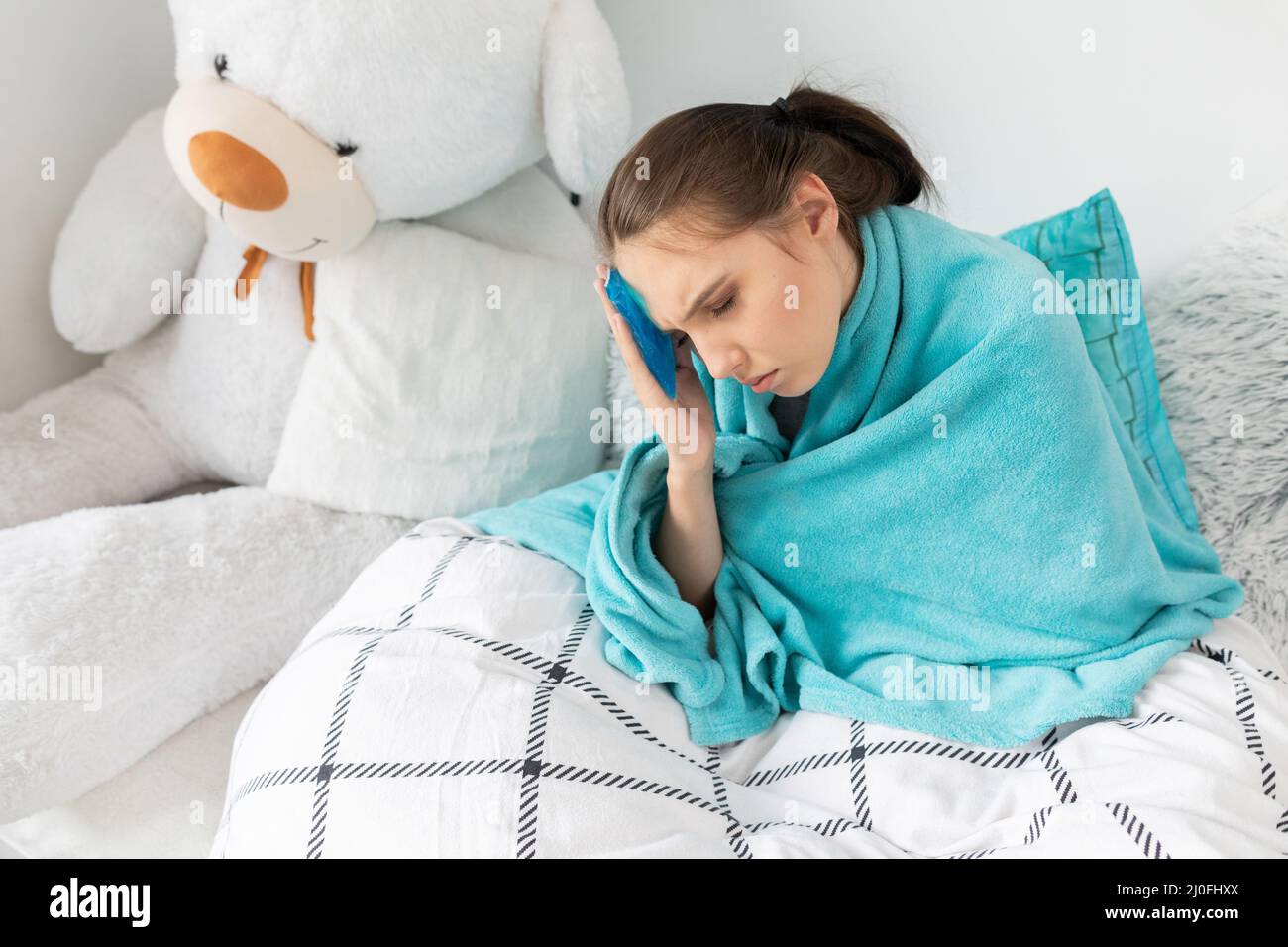 The teenager puts cold compresses on her head to reduce the high ...