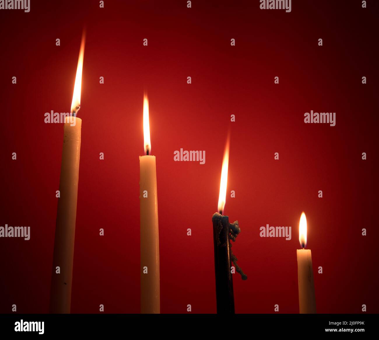Holy religious candles burning on a red background Stock Photo - Alamy