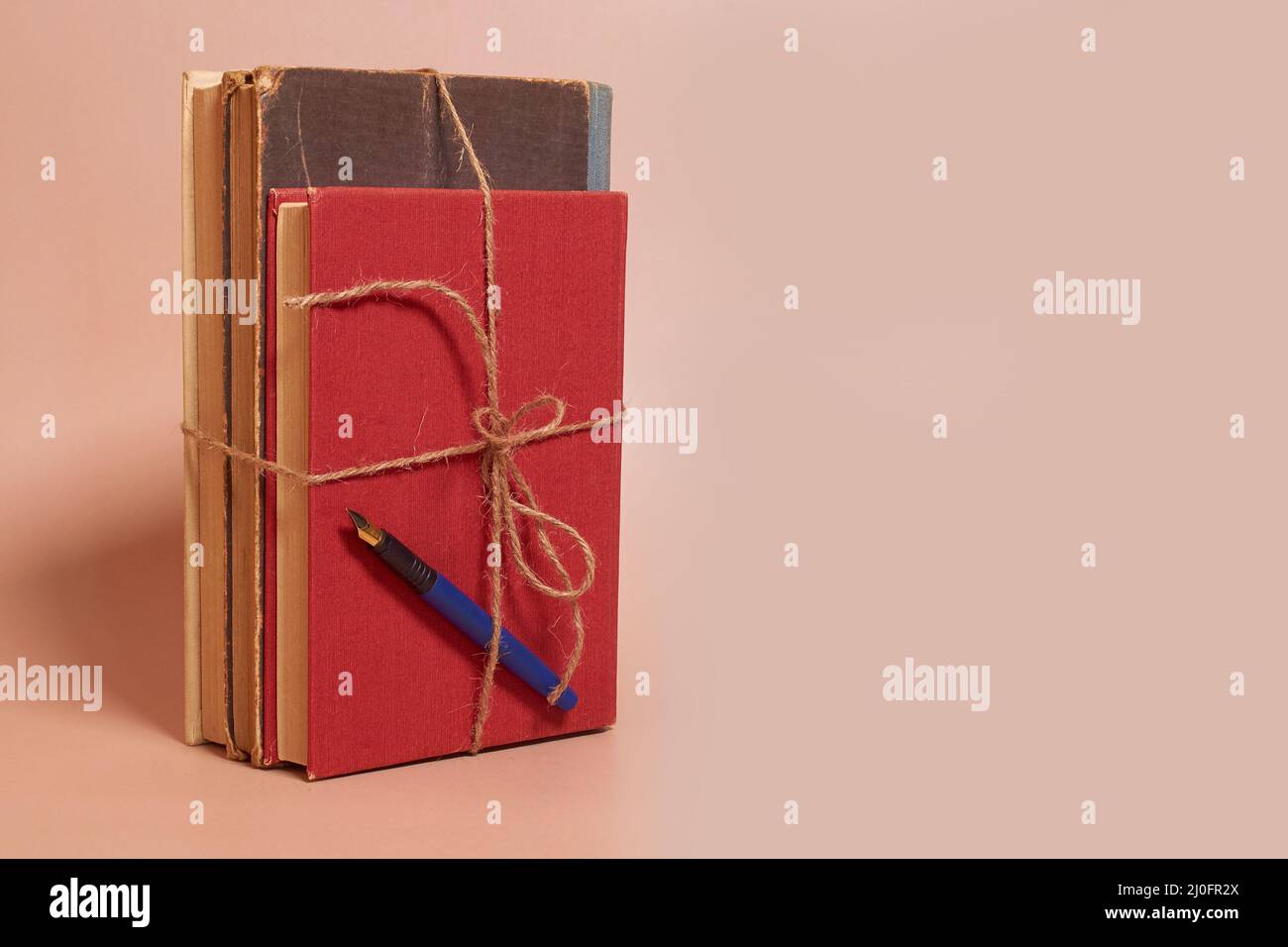 A stack of old battered books tied with a jute rope and a fountain pen ...