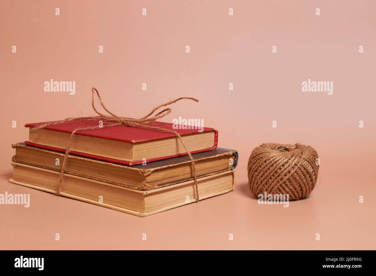 A stack of old battered books tied with jute rope, a coil of jute rope ...