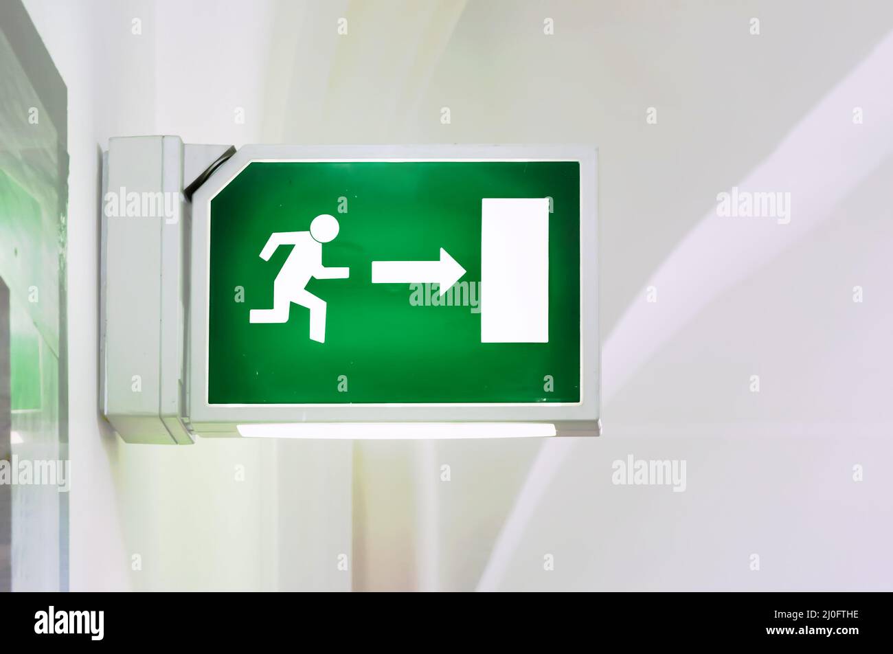 Illuminated green emergency exit sign Stock Photo - Alamy