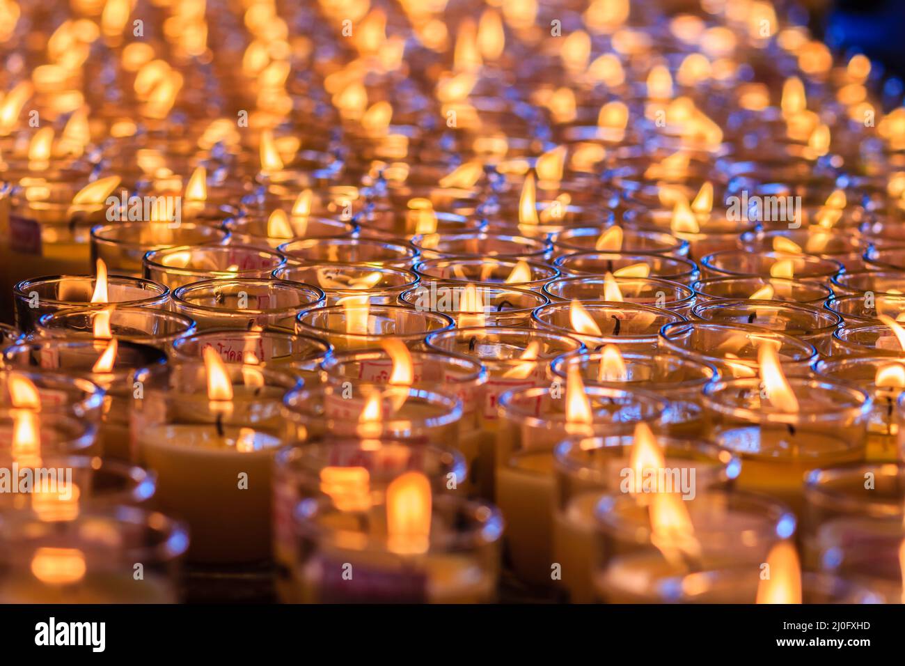 Beautiful red-orange light of many worship candles Stock Photo - Alamy