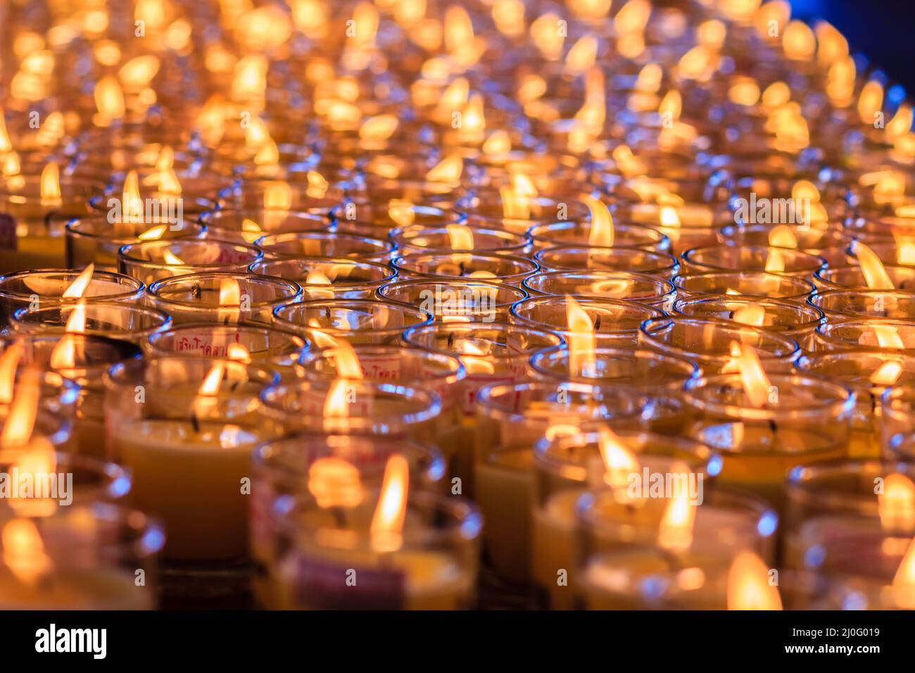 Beautiful red-orange light of many worship candles Stock Photo - Alamy