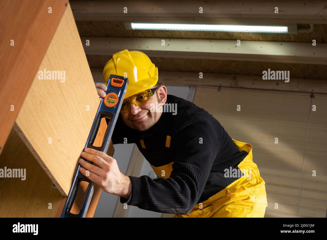 The builder checks with a spirit level that the cabinet is made ...