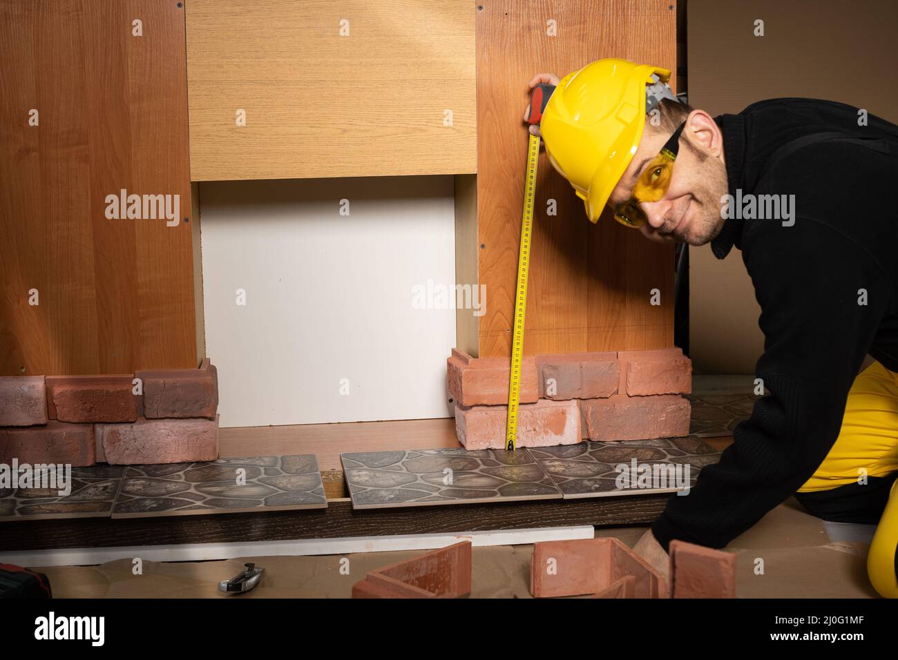 The construction worker looks at the camera and smiles while measuring ...