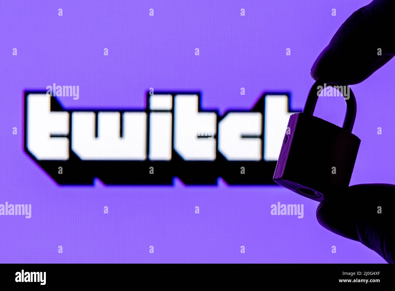 Fingers hold a closed security lock on the background of the Twitch ...