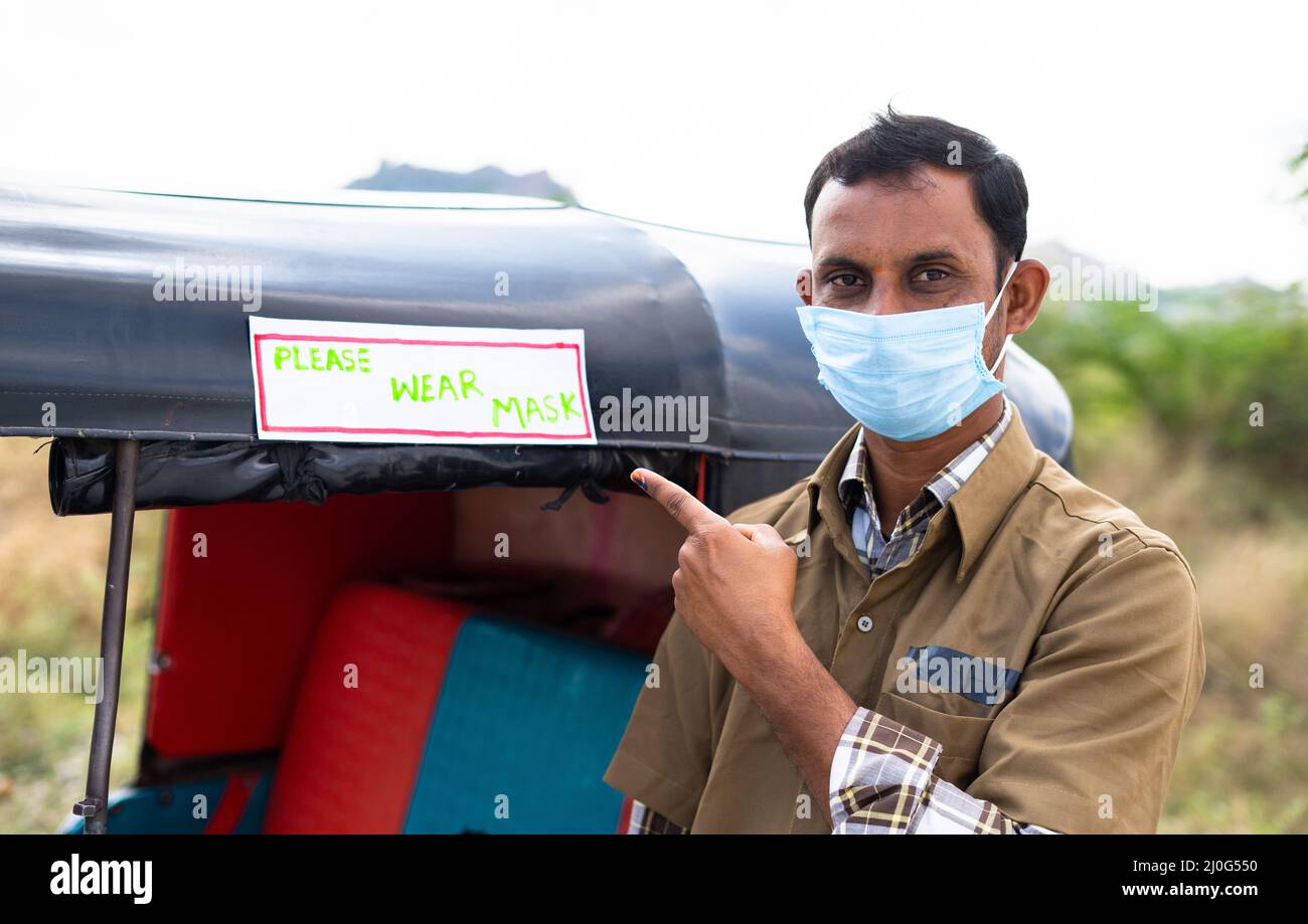 Auto driver in medical face mask with showing please wear mask sign ...
