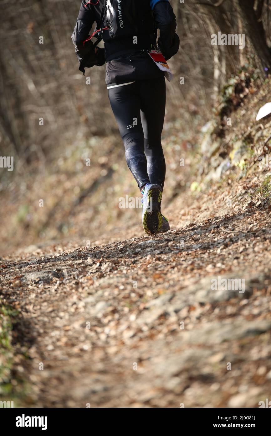 athlete running during a cross-country foot race on a path in the woods ...