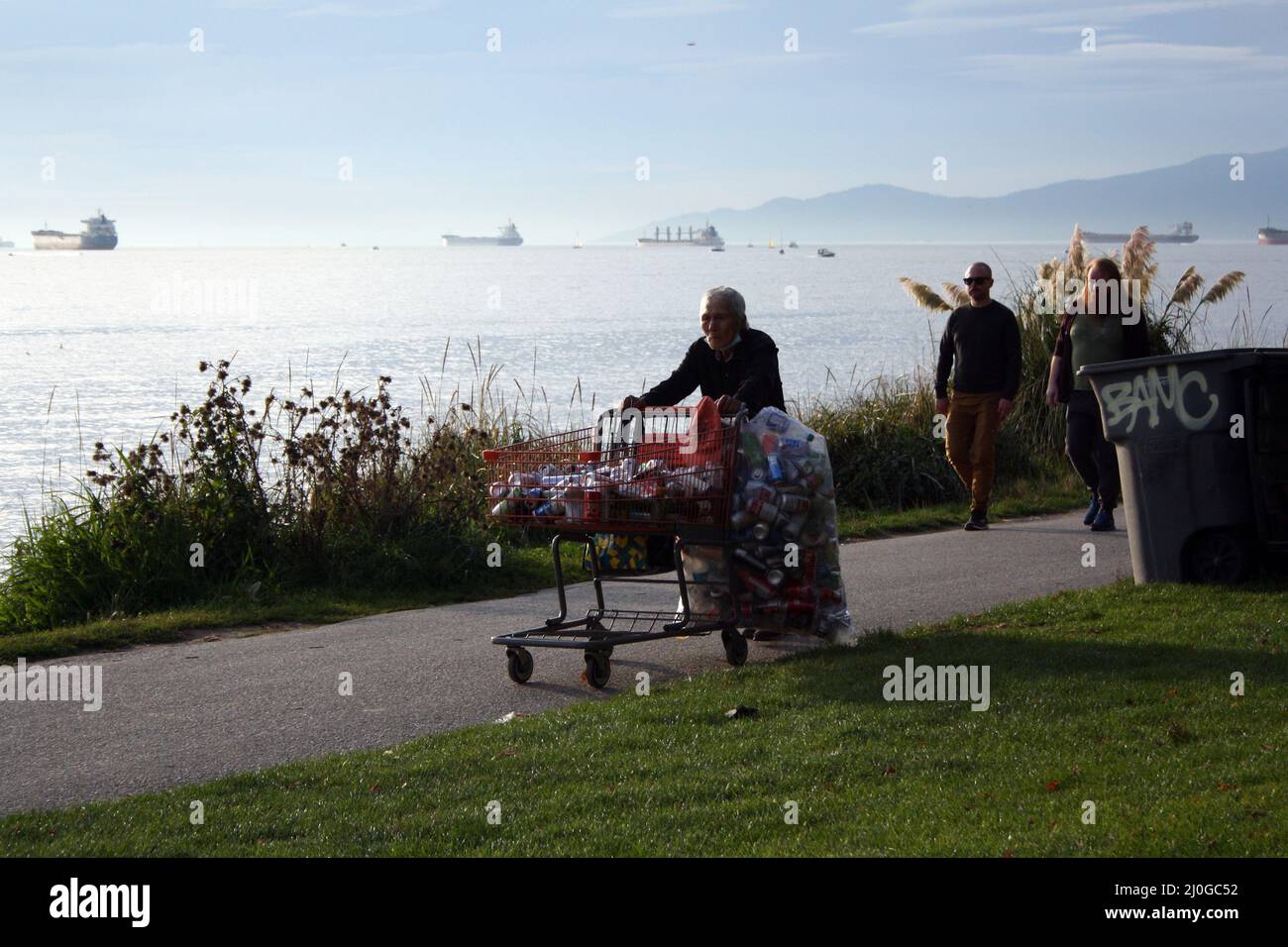Homeless man pushing a cart with empty bottles and cans Stock Photo - Alamy