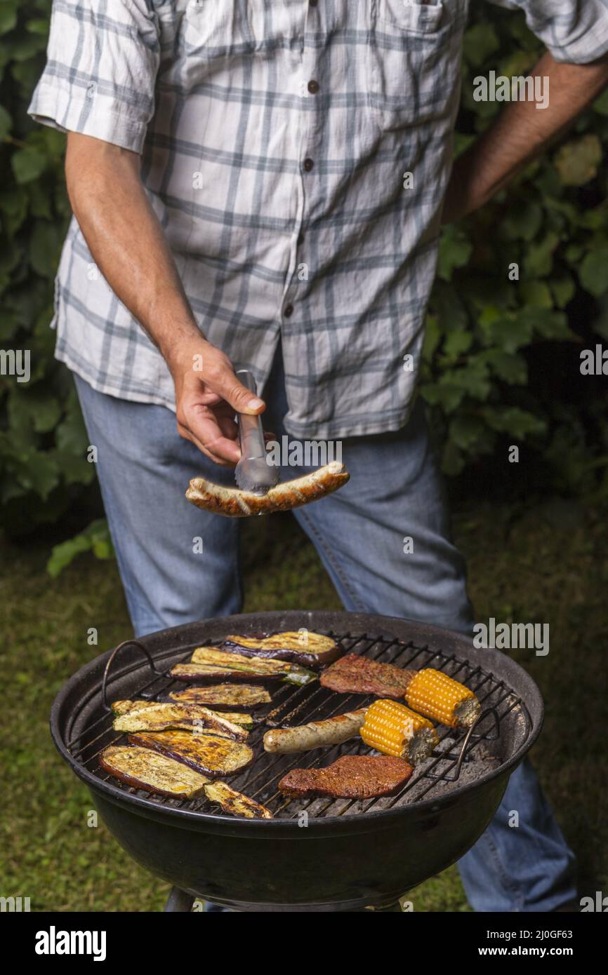 Mann ha lt eine wurst am grill hi-res stock photography and images - Alamy