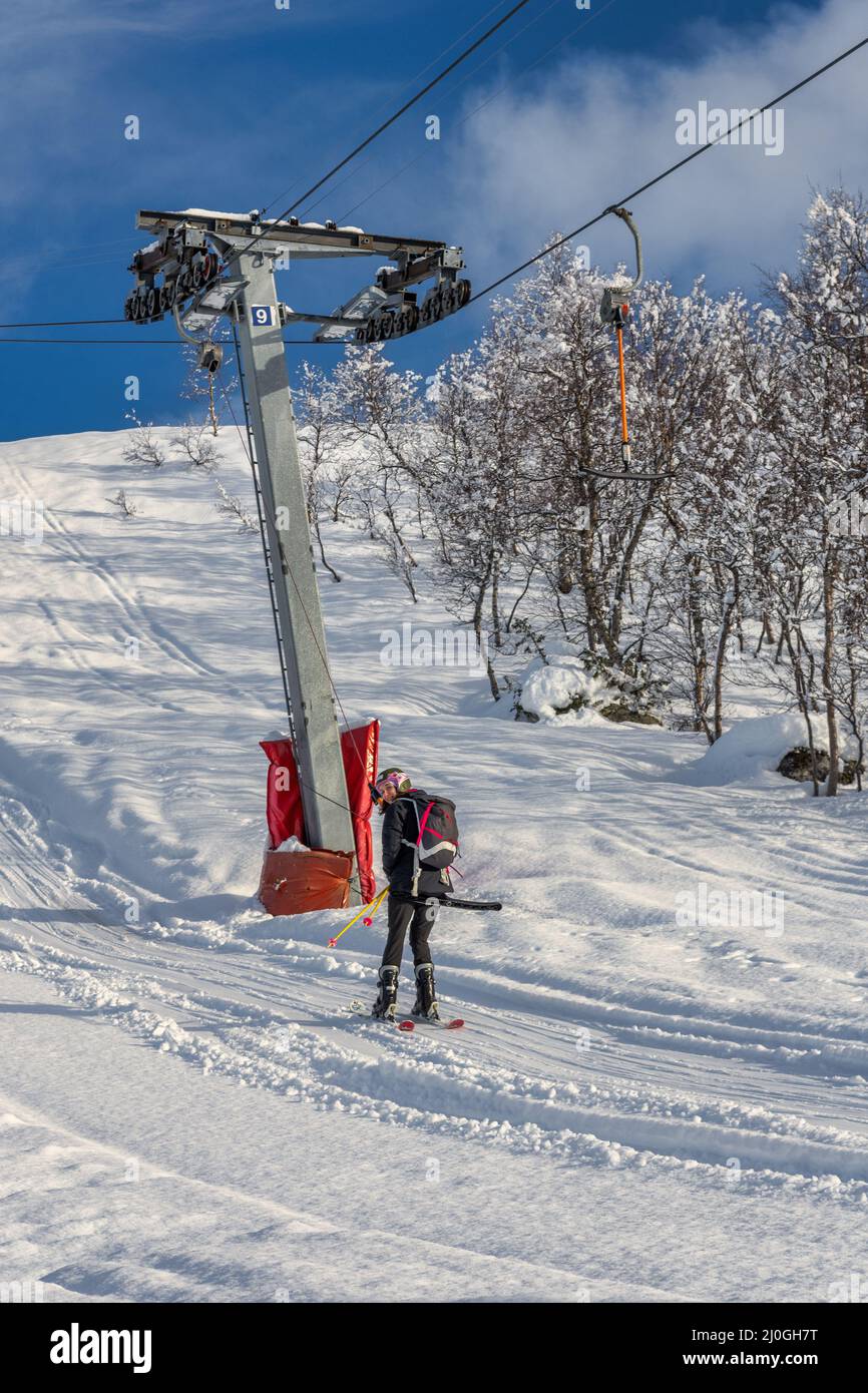 Skiing Woman with brown hair and black ski wear, smiling, looking back ...
