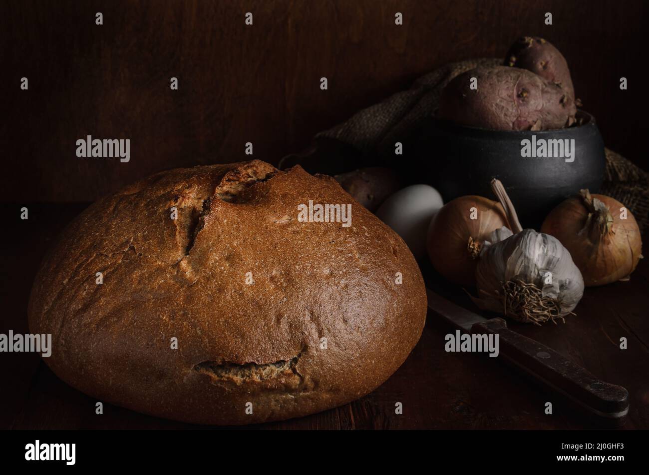 Loaf of bread in rustic style on dark wooden background Stock Photo - Alamy
