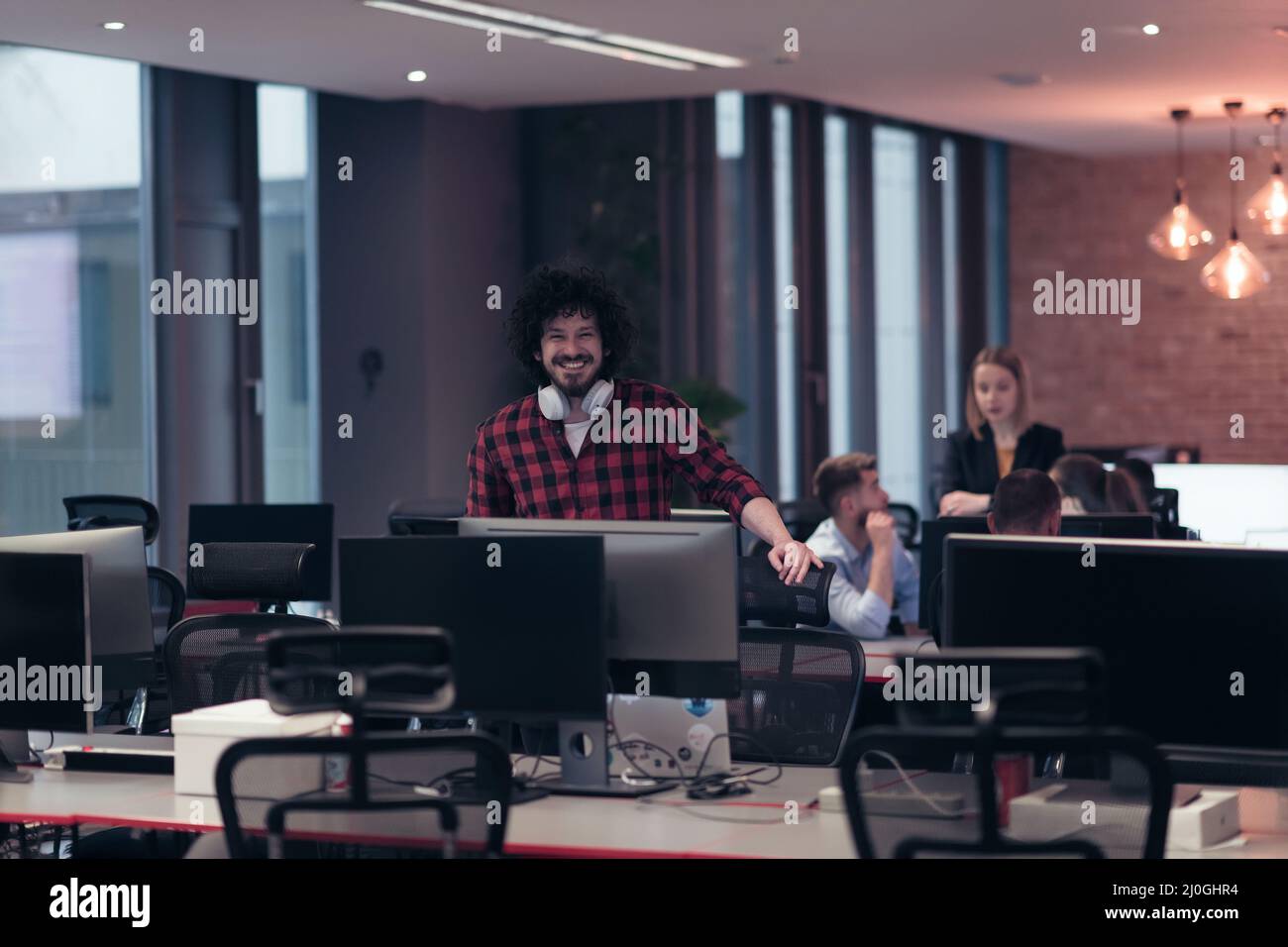 A young man with an Afro haircut stands in a modern office surrounded ...