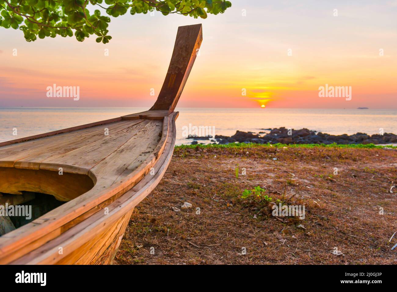 Wooden boat on sunset beach Stock Photo - Alamy