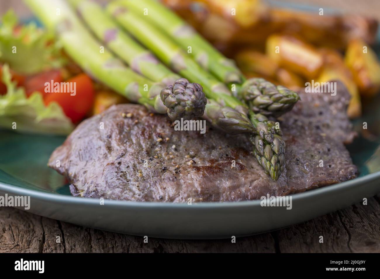 Asparagus on grilled steak with fries Stock Photo - Alamy