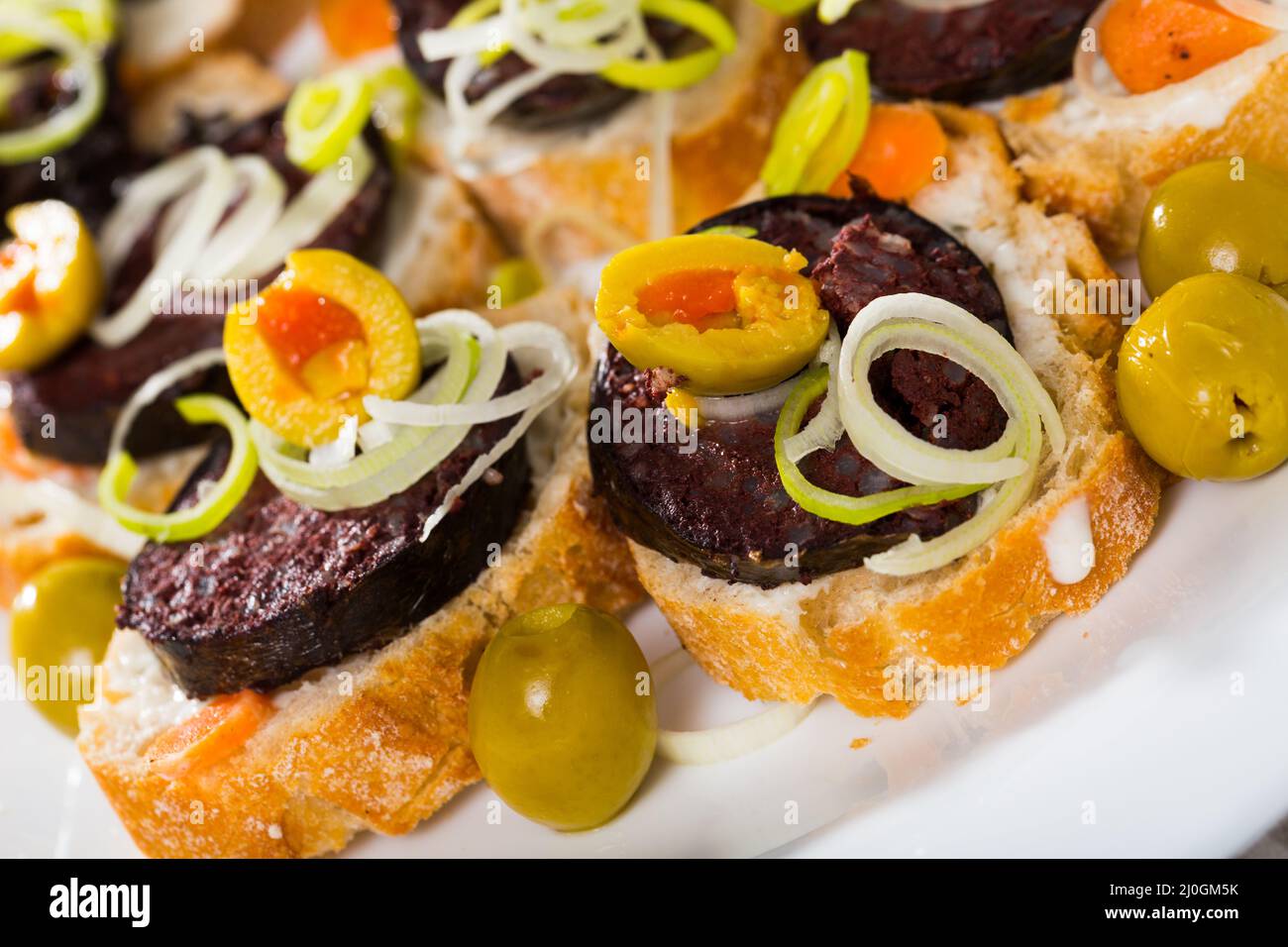 Image of tasty canapes from blood sausage with bread and olives Stock ...