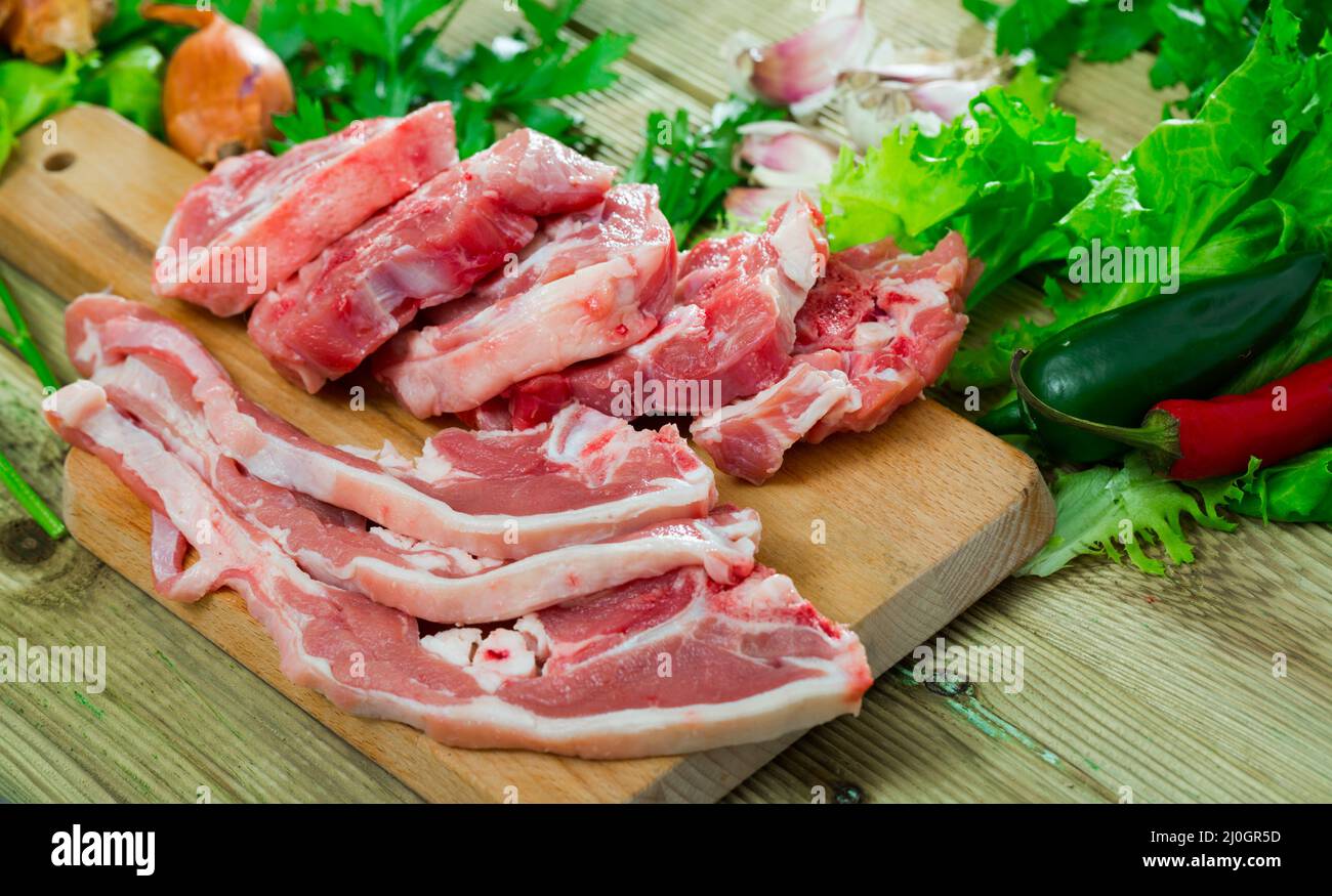 Fresh slices of mutton and vegetables assortment on natural wooden desk ...