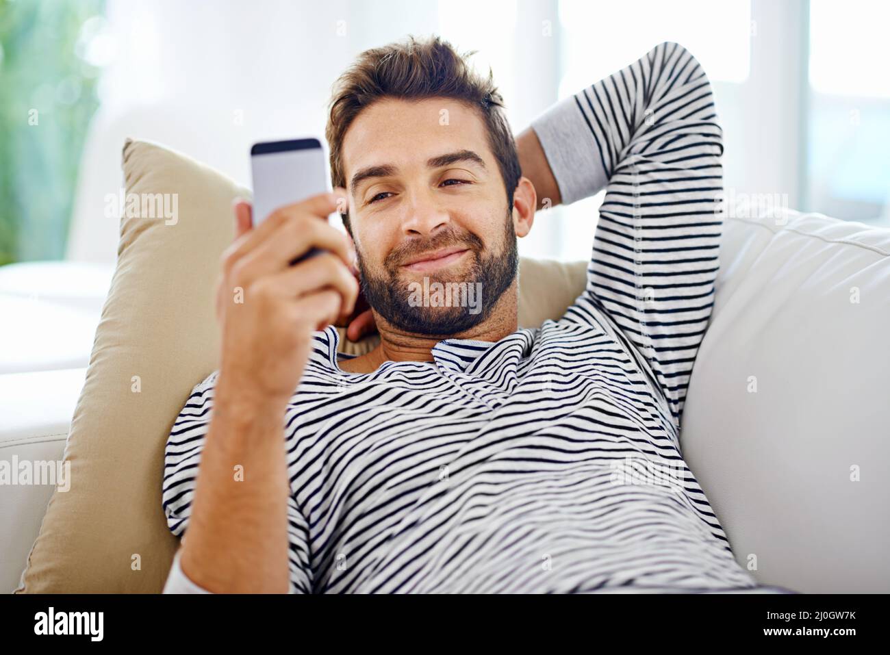 Looking through his options. Man looking at his cellphone at home Stock ...