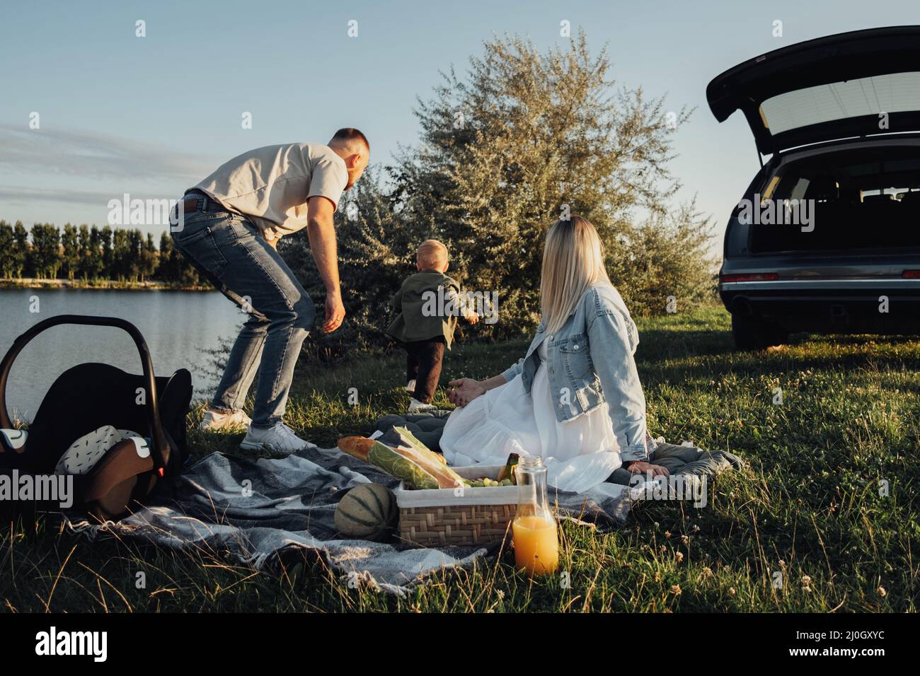 Young Family with Toddler Son Enjoying Picnic by the Lake on a Weekend ...