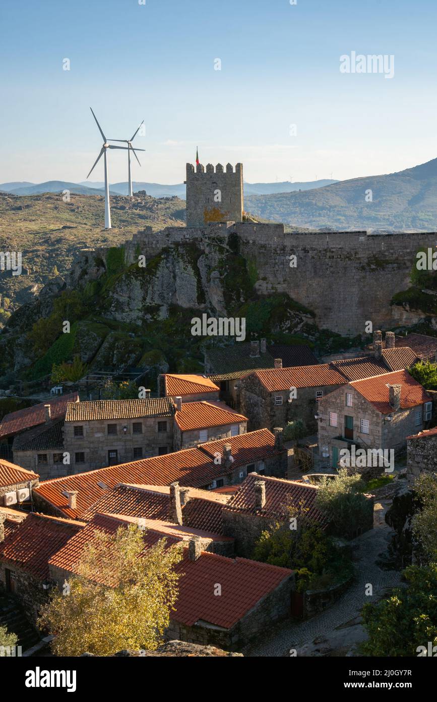 View of Sortelha castle and antique stone houses and wind turbines, in ...