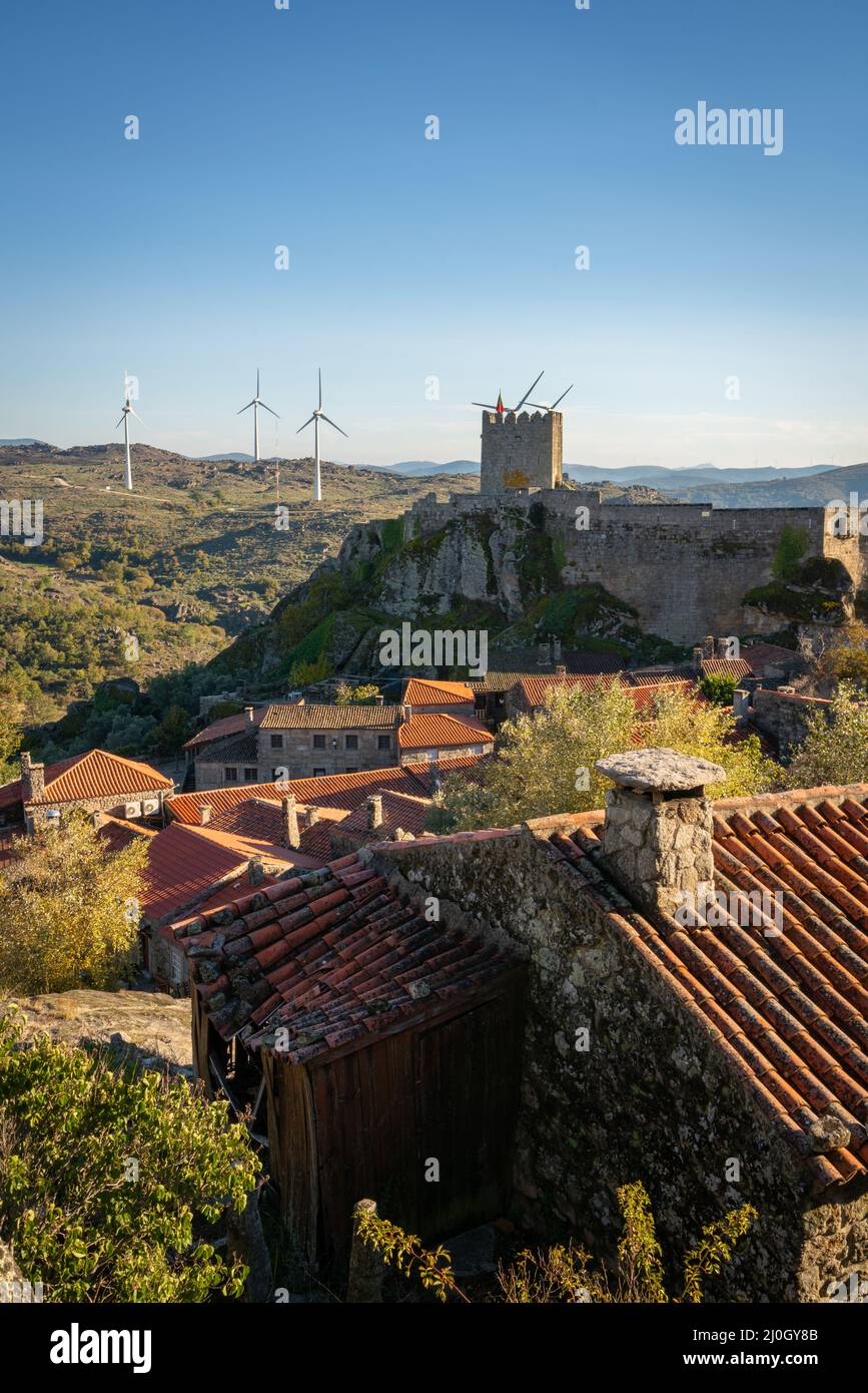 View of Sortelha castle and antique stone houses and wind turbines, in ...