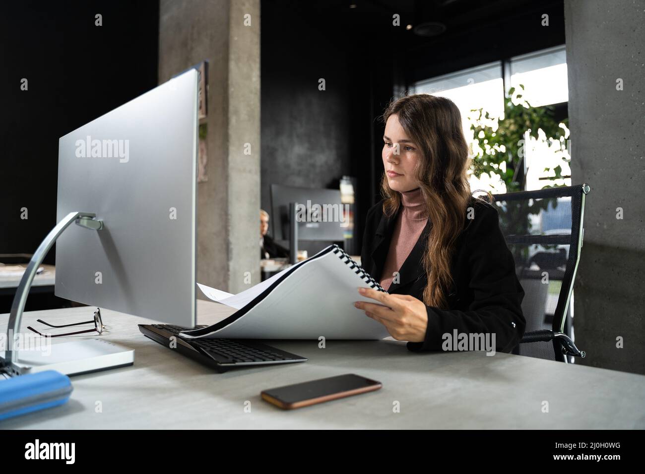 Young woman architect working with blueprints and technical design ...