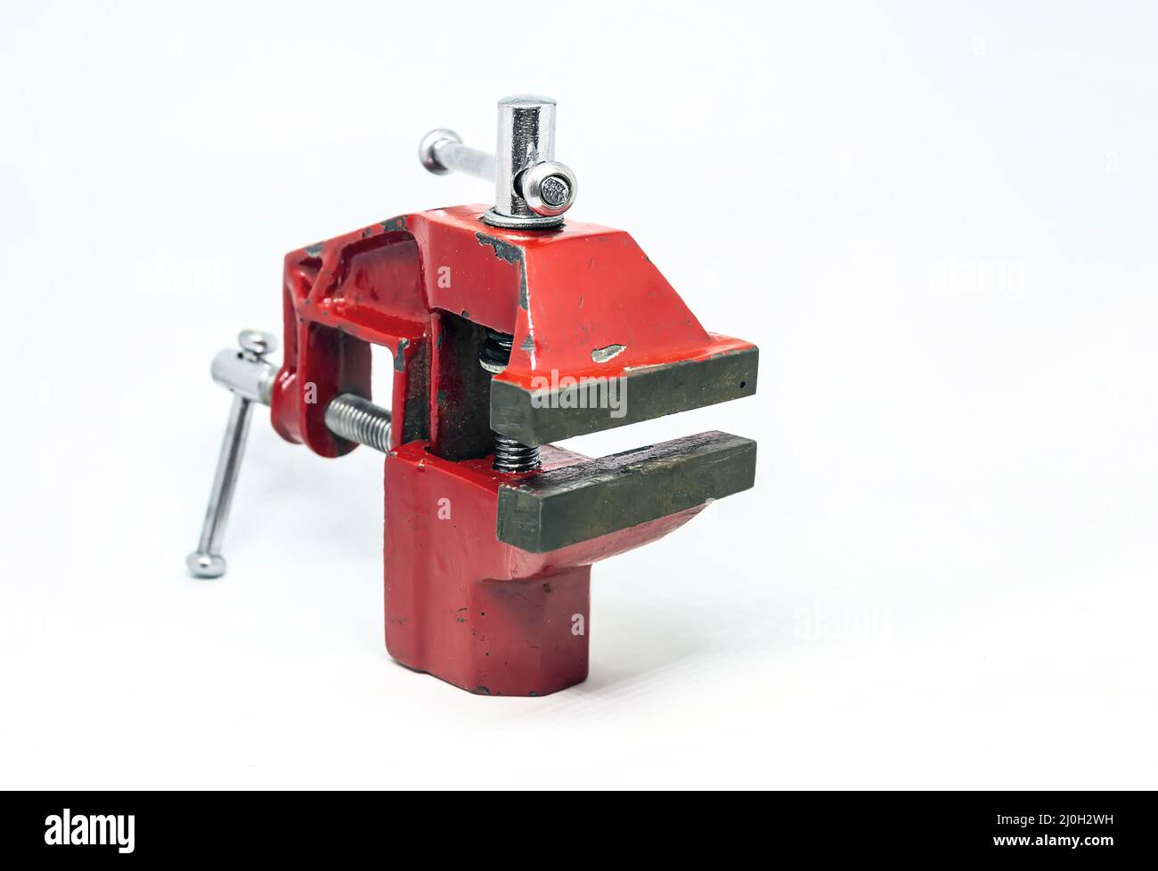 Close-up view of a red steel bench vise isolated on a white background ...