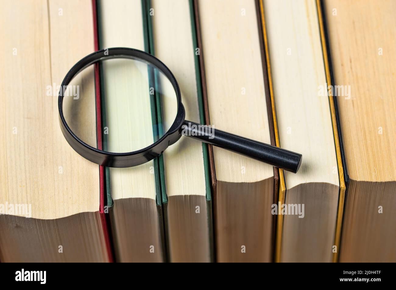 Magnifying glass over the stack of books at library Stock Photo - Alamy