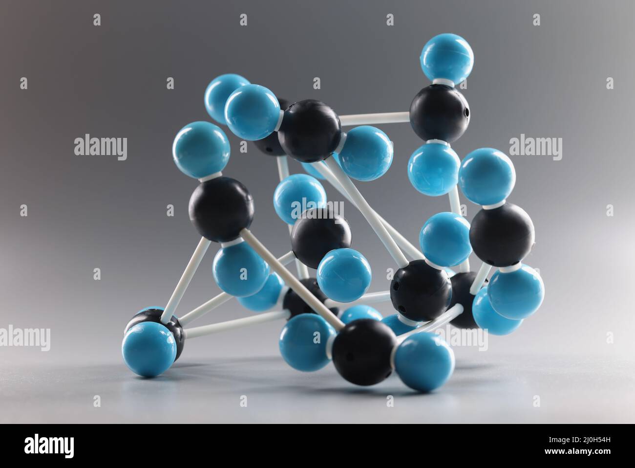 Molecular model structure, miniature on grey background, blue and black ...