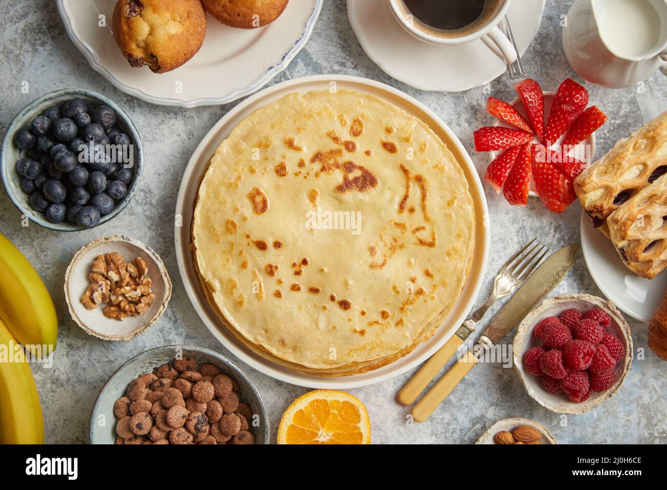 Breakfast table setting with fresh fruits, pancakes, coffee, croissants ...