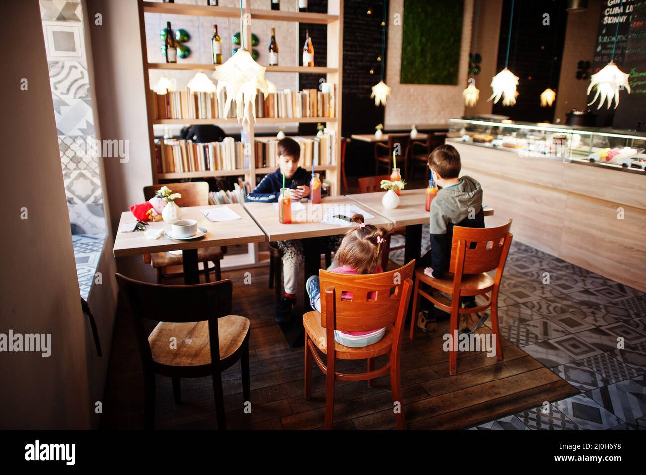 Kids sitting in cafe. Three children having rest Stock Photo - Alamy