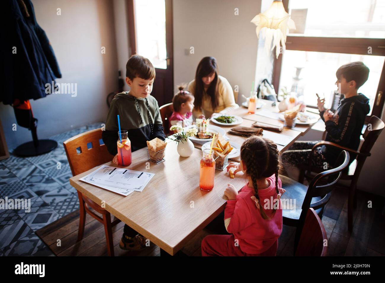 Mother with four kids spending time in cafe. Family lunch in the ...