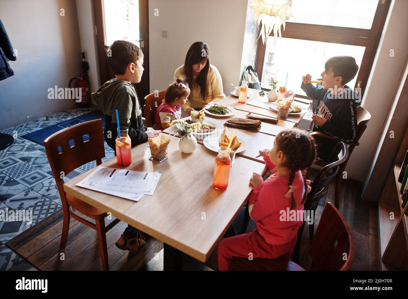 Mother with four kids spending time in cafe. Family lunch in the ...