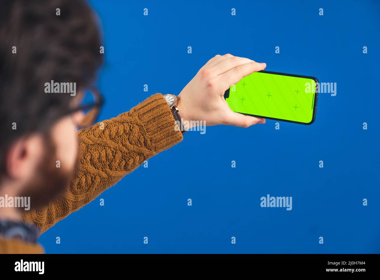 caucasian man holding a phone with green screen on it. Blue screen ...