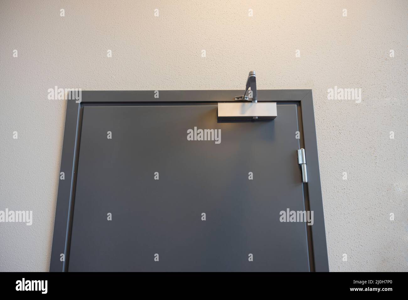 Close up view of entrance gray super-heavy metal door with closer and ...