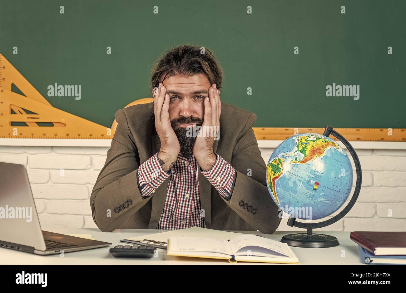 overworked male teacher feeling tired sitting in classroom, relax Stock ...
