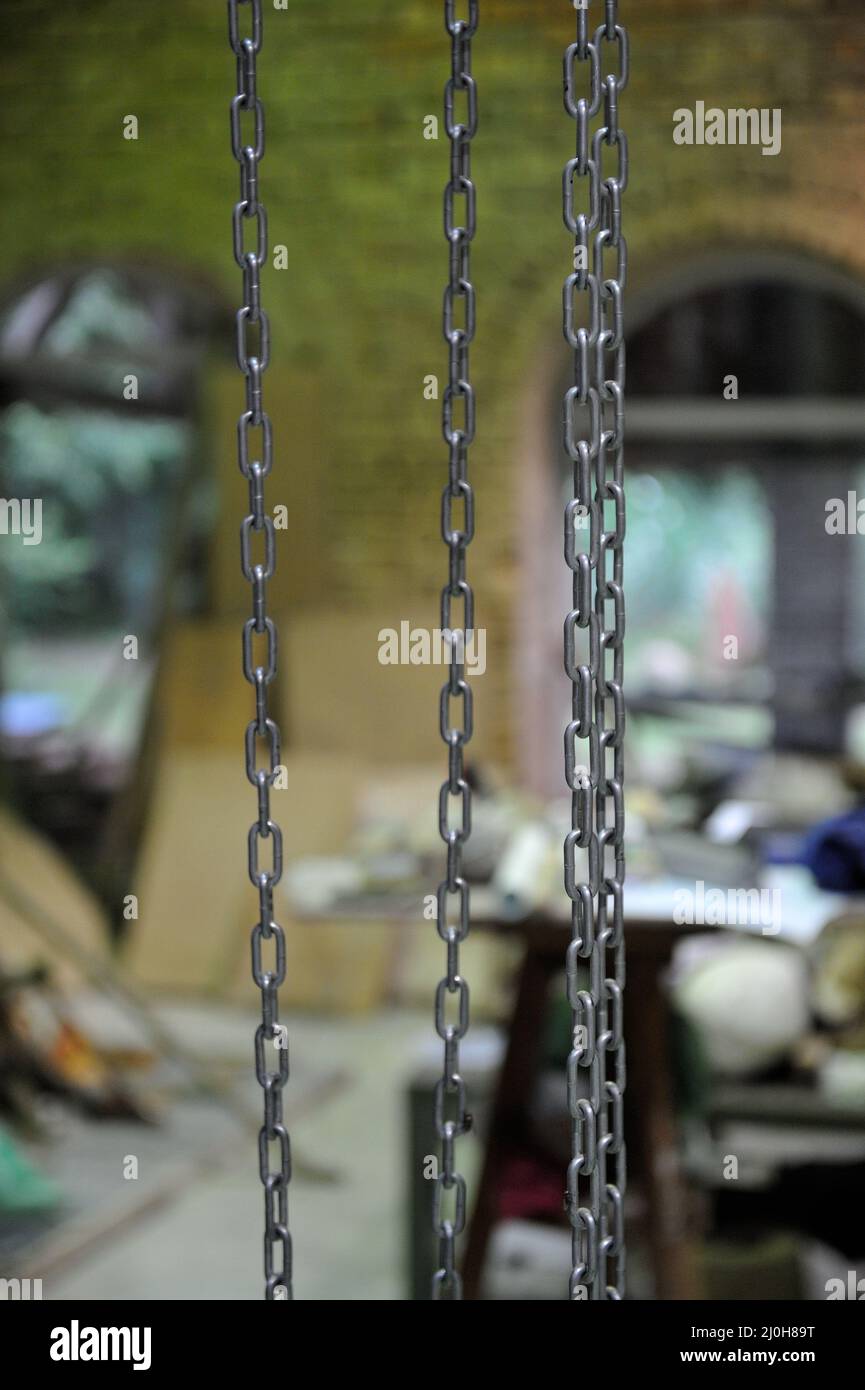 Vertical shot of silver chains hanging in a room on a blurred ...