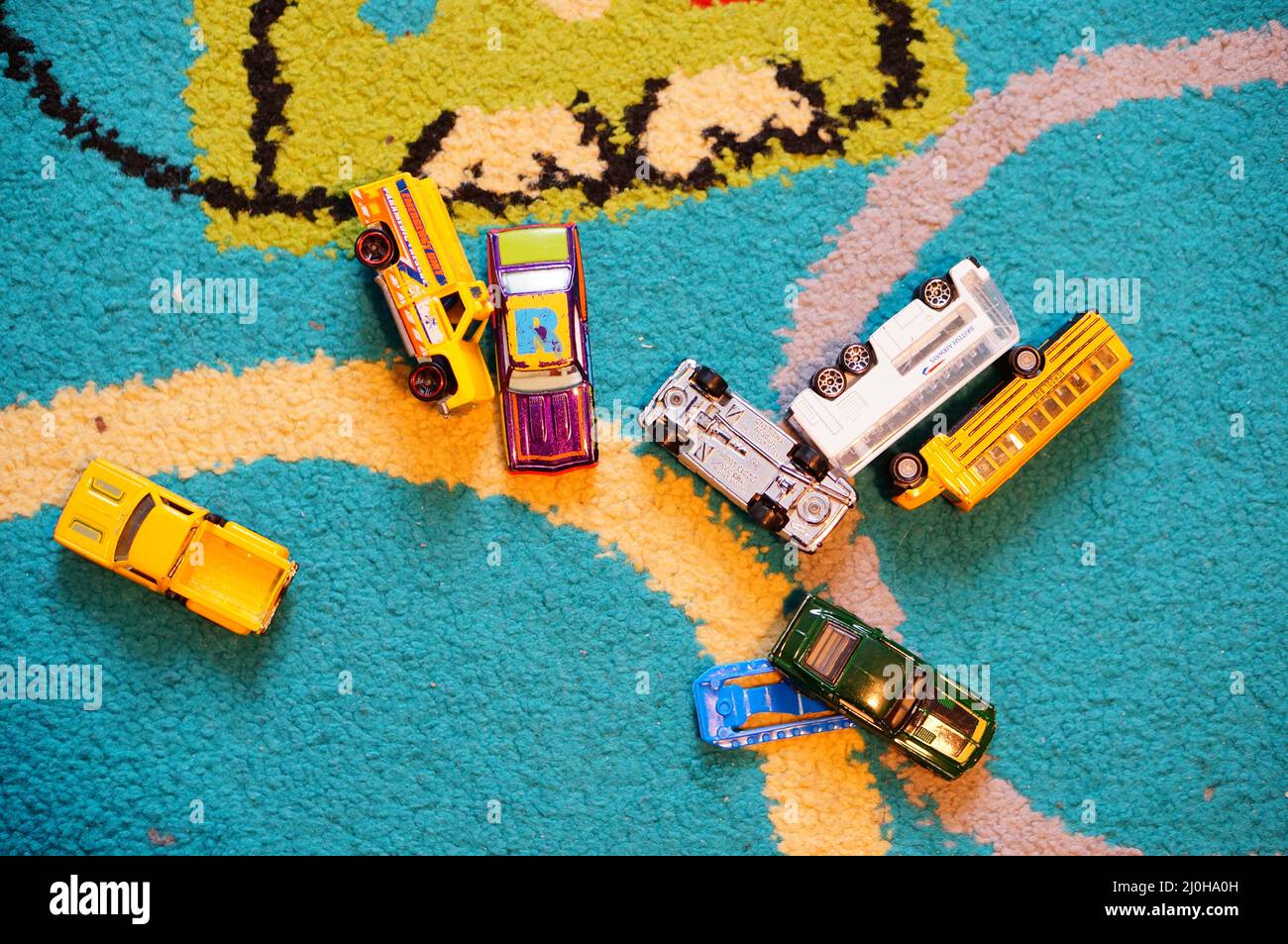A mix of toy model cars laying on a floor. Includes the brand Hot ...