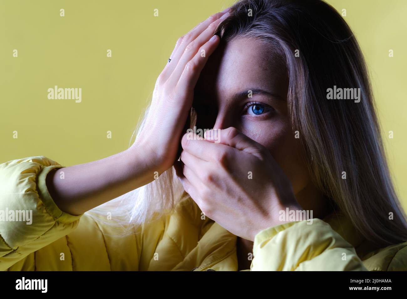 Blonde woman's hands covering her mouth and the eye on yellow ...