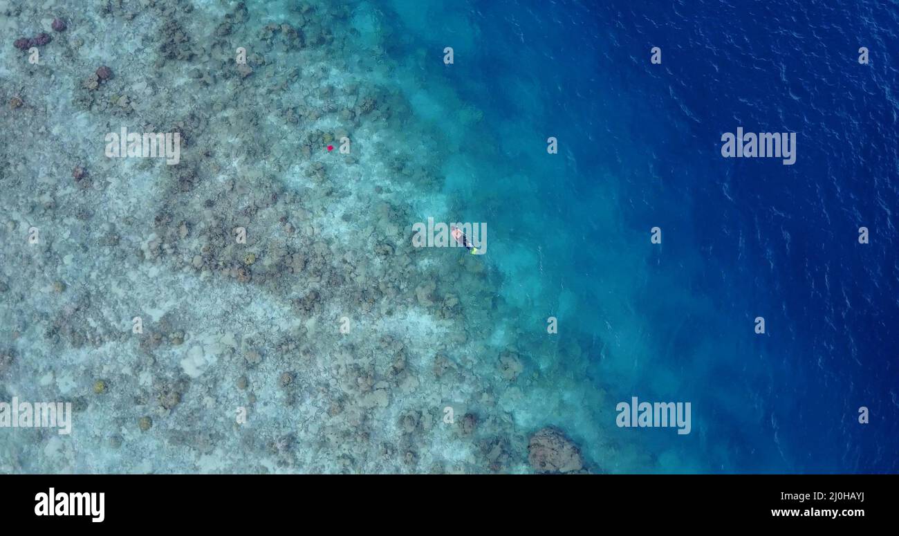 Aerial view of a male swimming in the ocean in Rasdhoo Island, Maldives ...