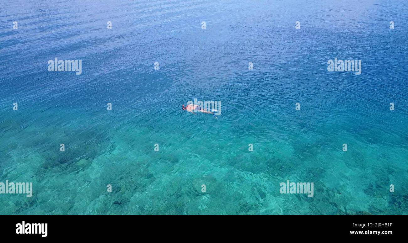 Aerial view of a male swimming in the ocean in Rasdhoo Island, Maldives ...