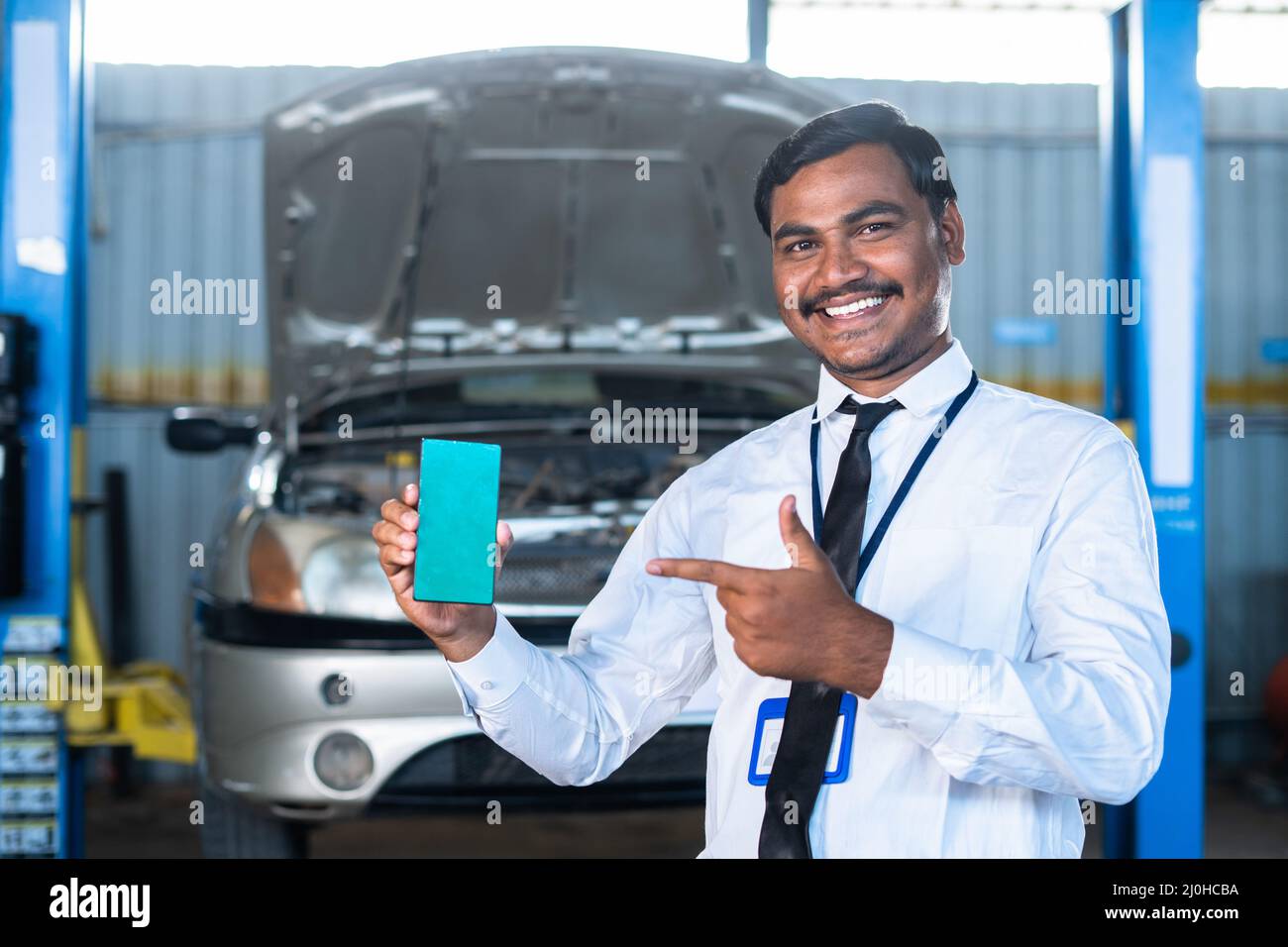 Executive at car garage showing green screen mobile phone by pointing ...