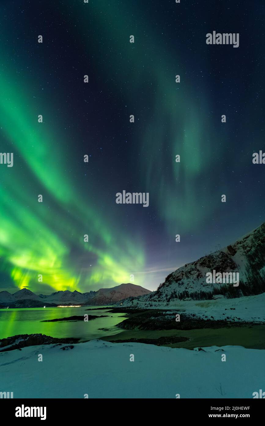 Vertical shot of the northern lights over the sea near Tromso, Norway ...