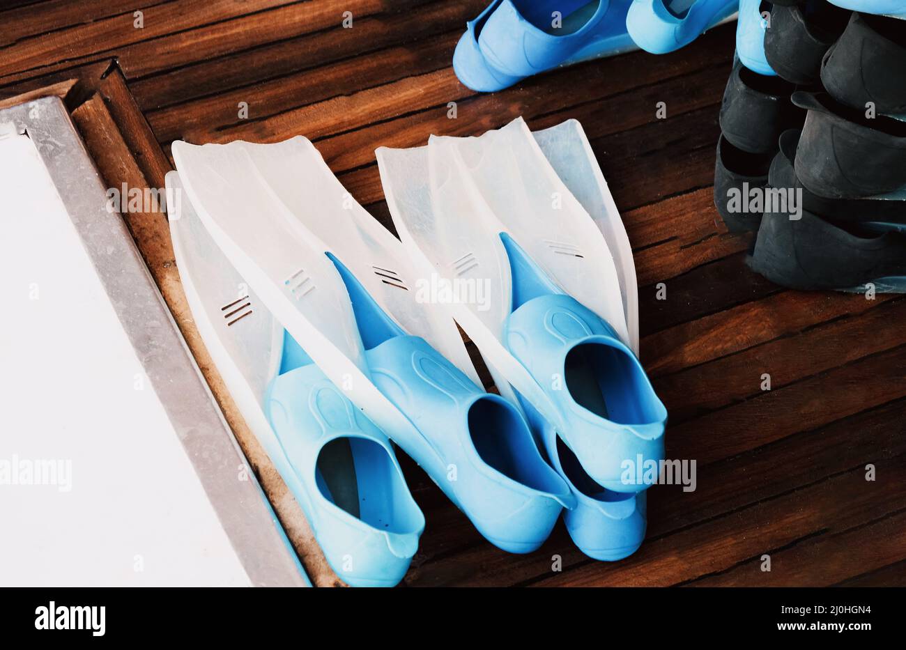 Two pairs of blue and white flippers on a wooden floor on a boat Stock ...