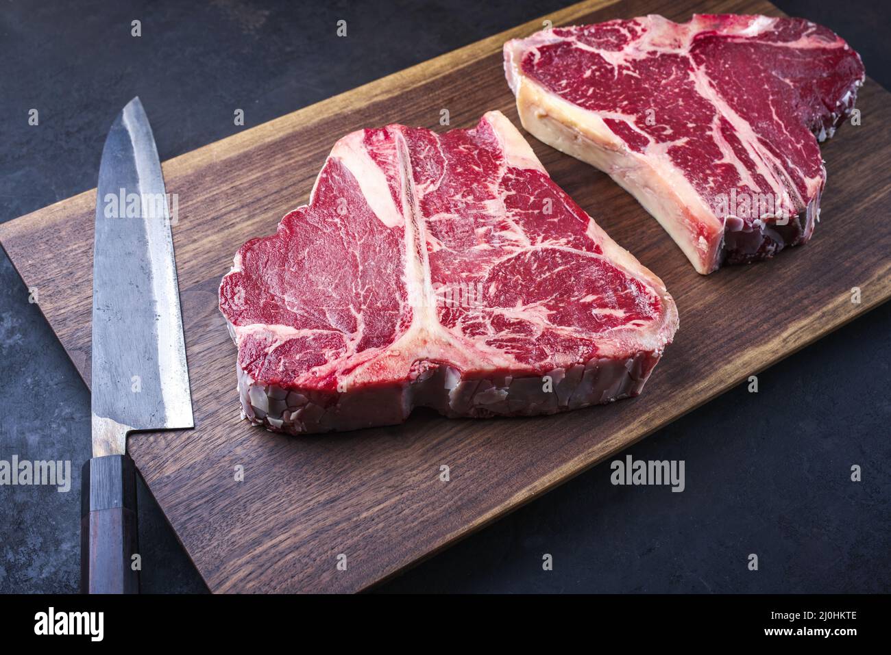Two raw dry aged wagyu porterhouse beef steaks offered as close-up on ...